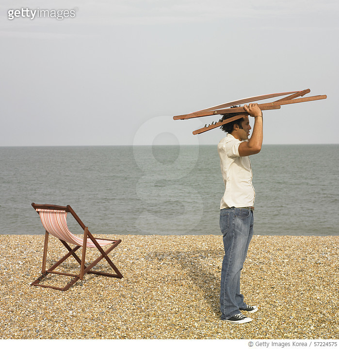 57224575 | 게티이미지코리아 | Young man with lounge chair above his head at ...